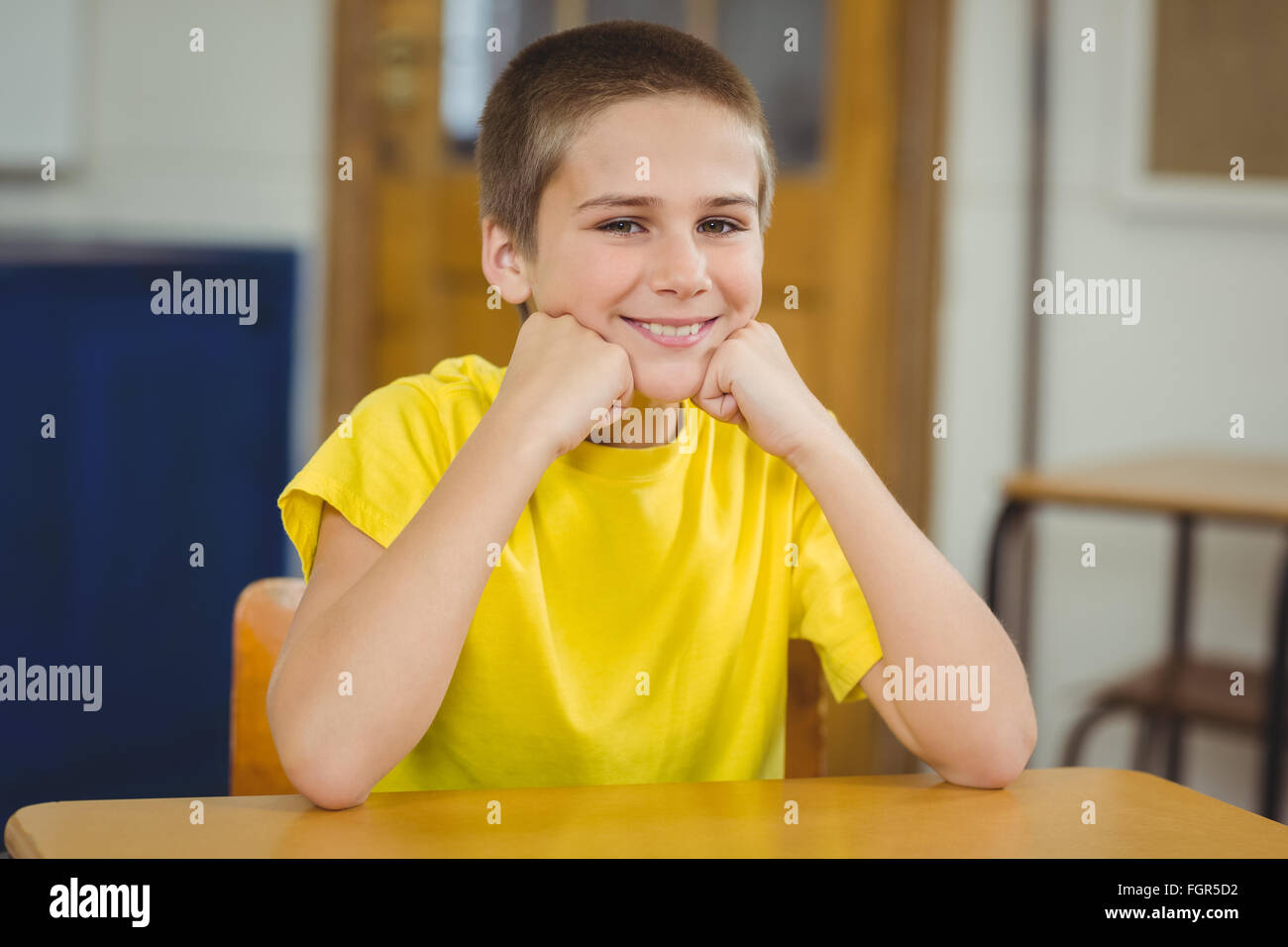 Smiling pupil sitting at his desk in a classroom Stock Photo - Alamy