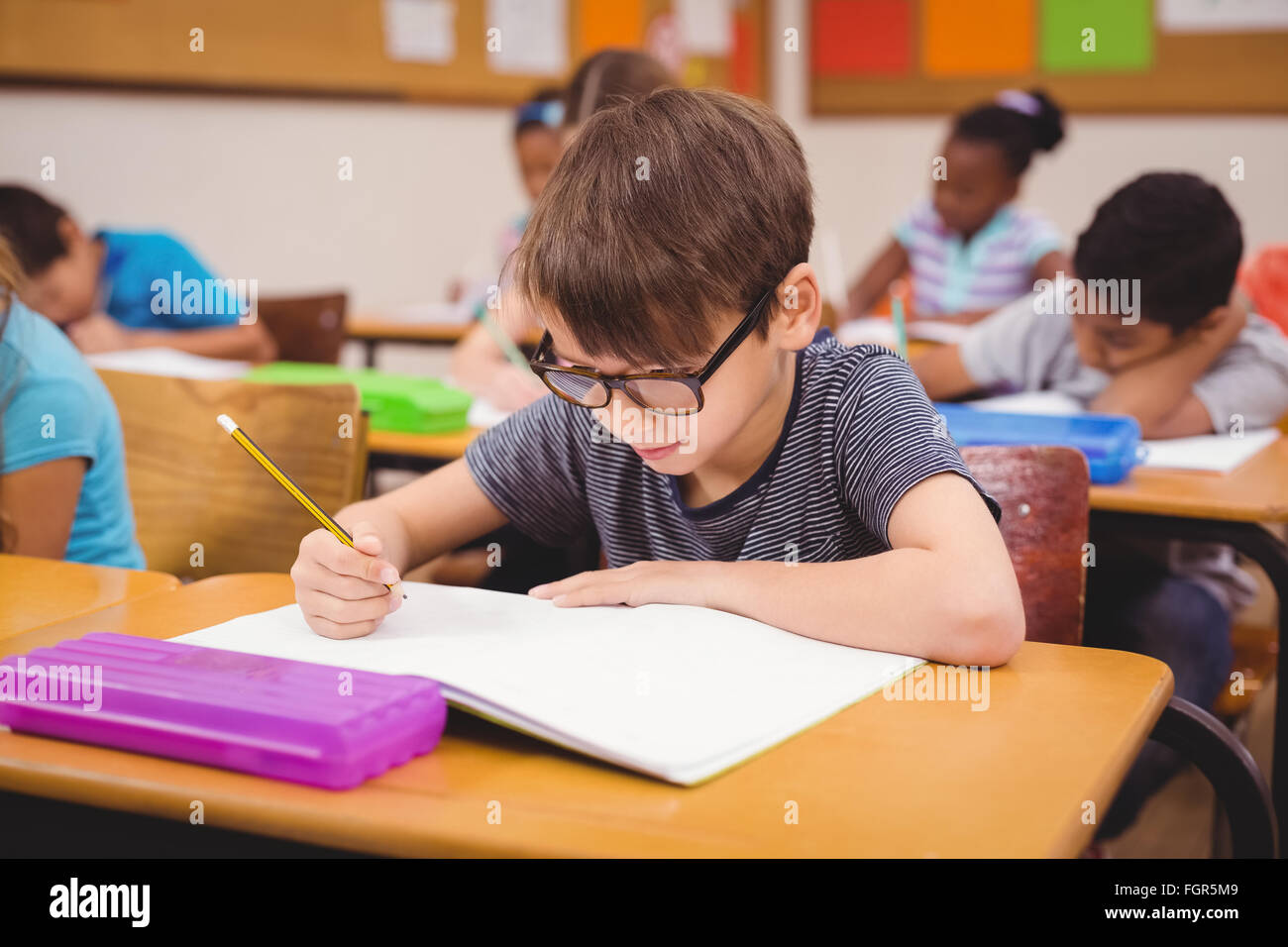 Little boy working at his desk in class Stock Photo - Alamy