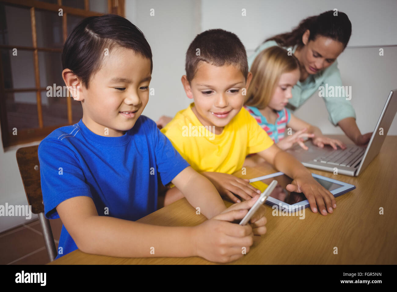 Cute pupils in class using laptop and tablet Stock Photo - Alamy