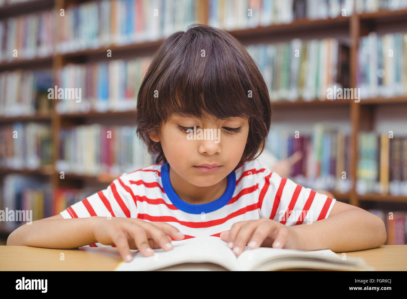Pupil reading book at desk in library Stock Photo - Alamy