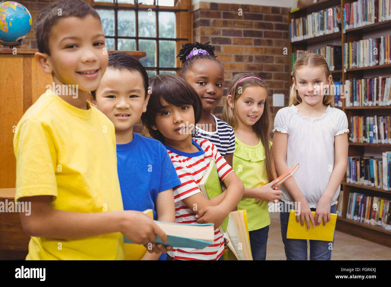 Pupils holding books from shelf in library Stock Photo - Alamy
