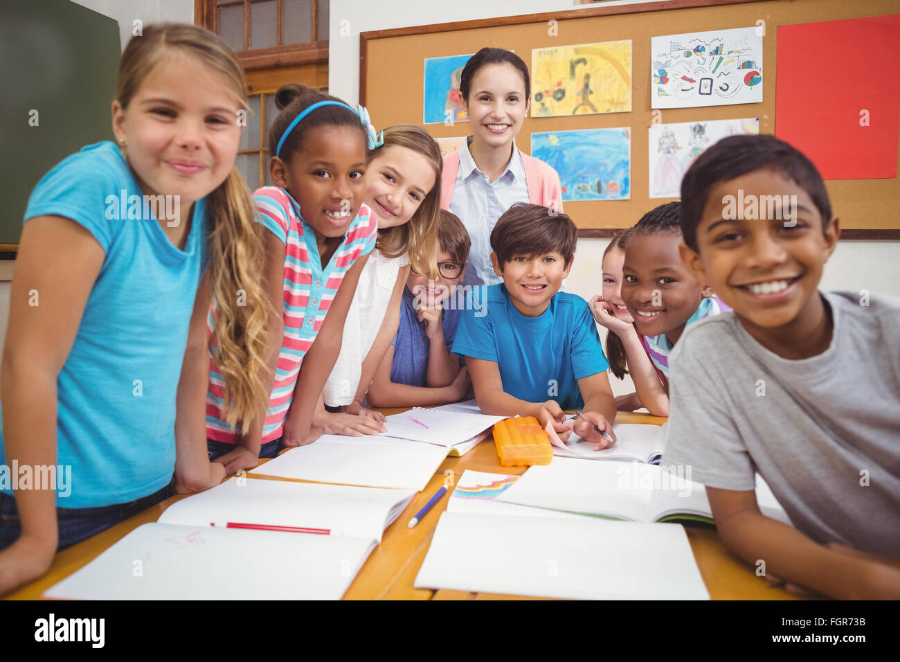 Teacher and pupils working at desk together Stock Photo - Alamy
