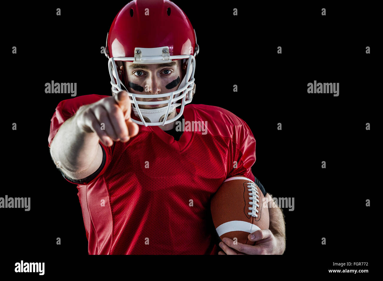 Portrait of american football player holding football and pointing to ...