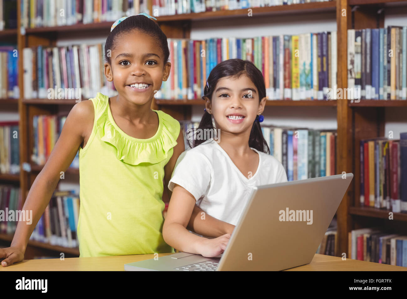 Smiling pupils using laptop in the library Stock Photo - Alamy