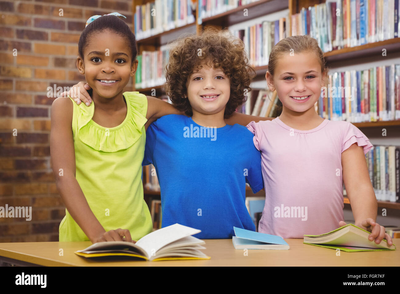 Happy pupils reading a library book Stock Photo - Alamy