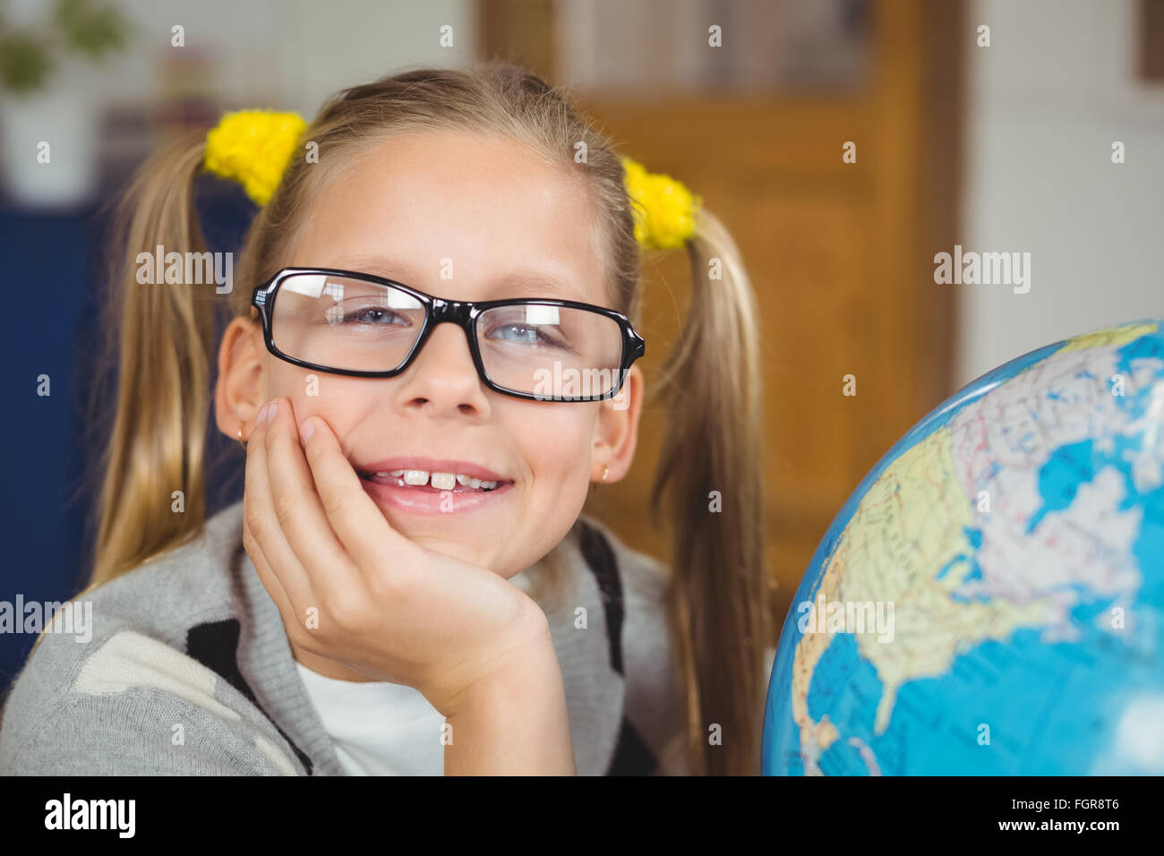 Cute pupil smiling next to globe in a classroom Stock Photo - Alamy