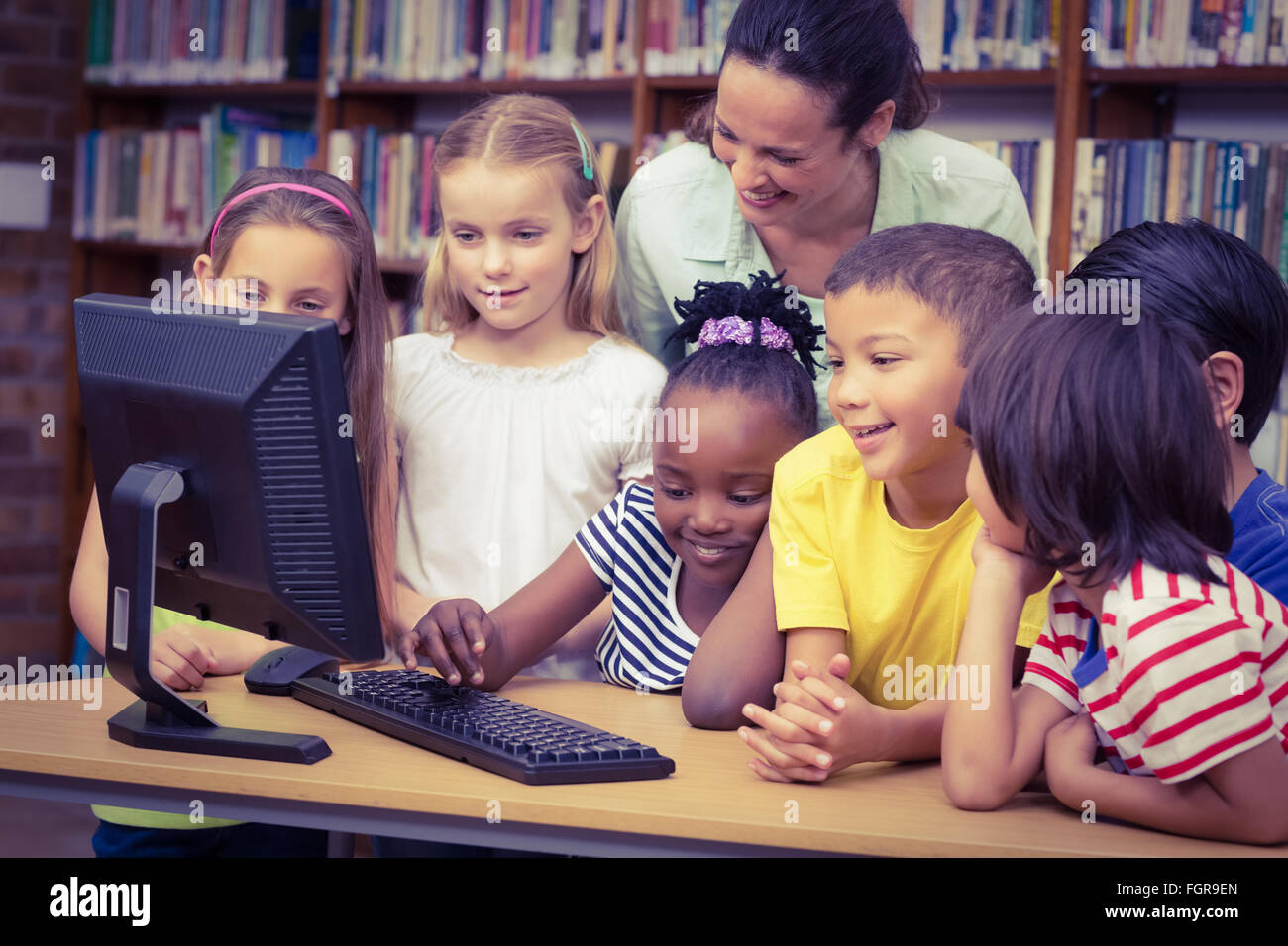 Pupils and teacher in the library using computer Stock Photo - Alamy