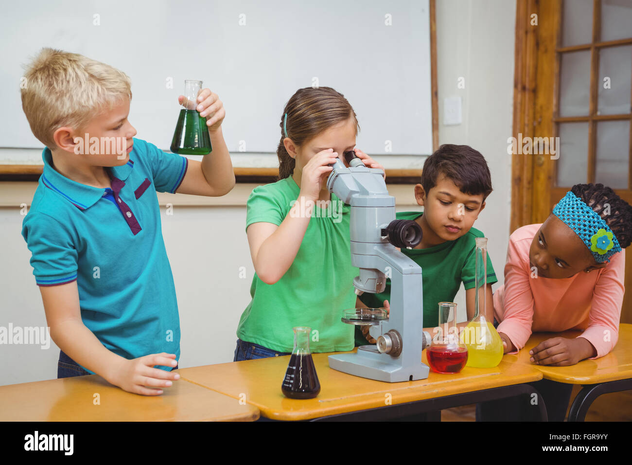 Students using science beakers and a microscope Stock Photo - Alamy