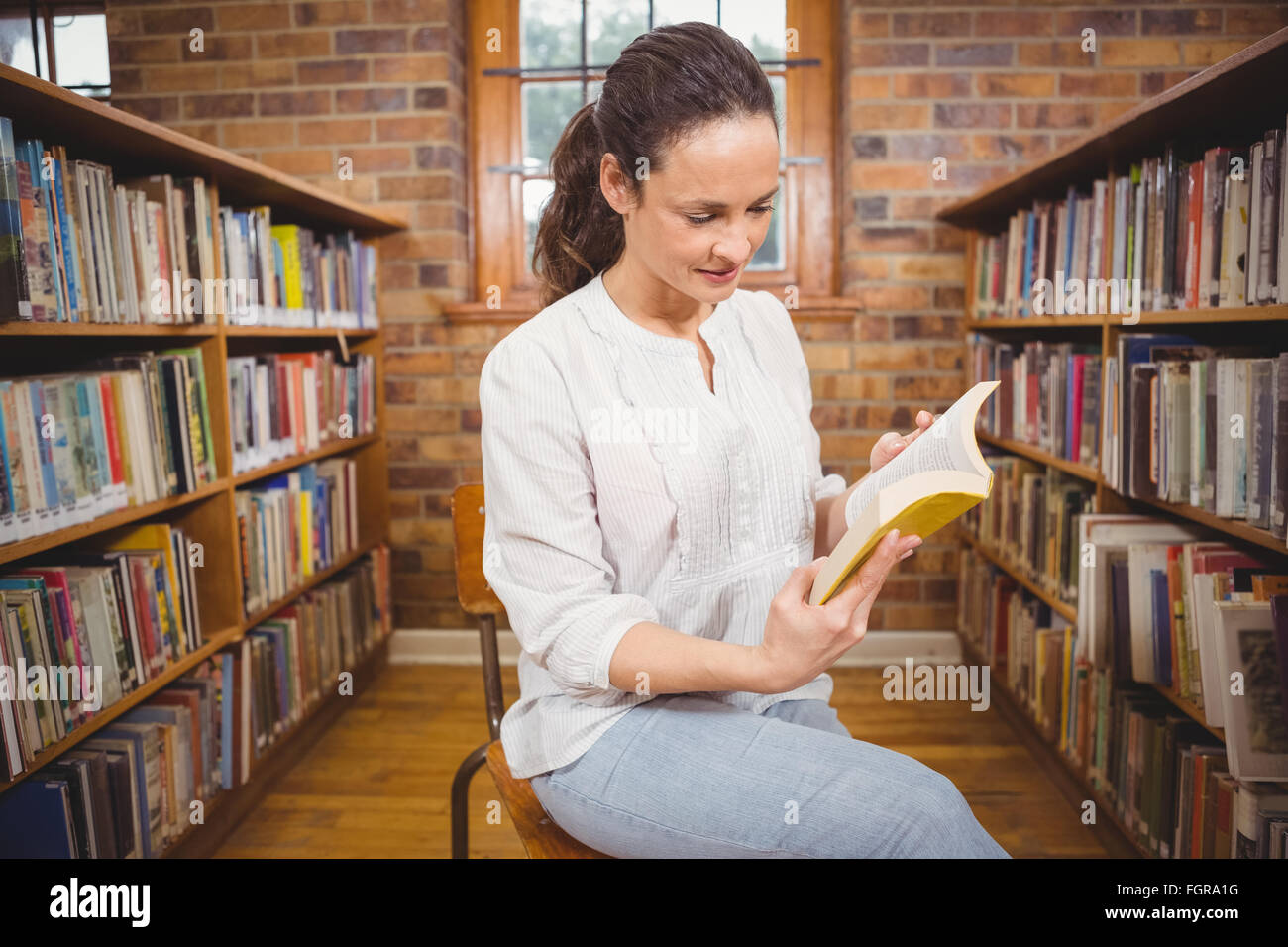 Smiling teacher reading a book Stock Photo - Alamy