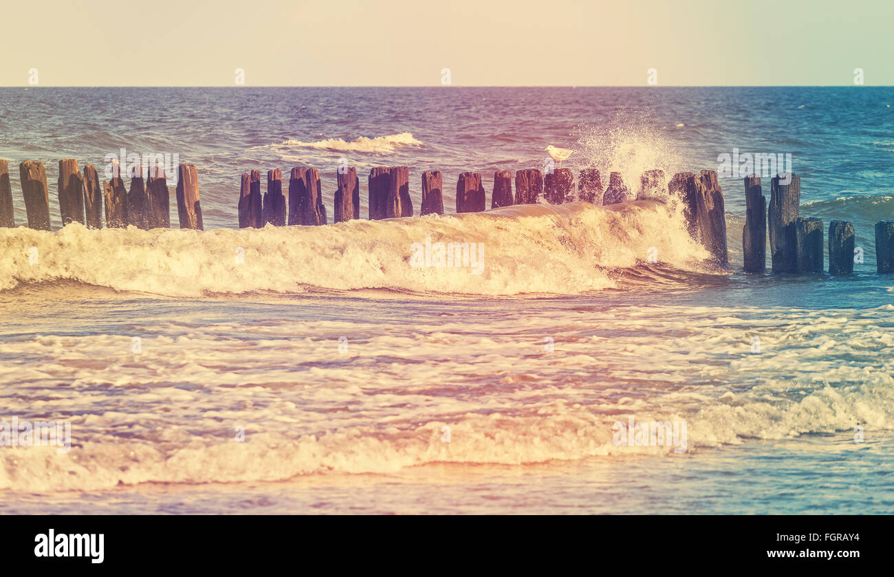 Retro stylized picture of wave crashing against wooden posts Stock ...