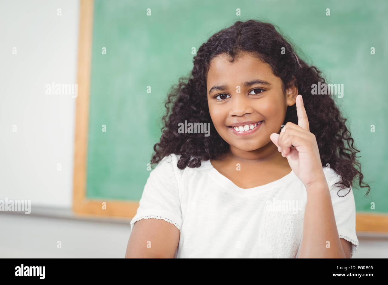 Smiling pupil raising hand in a classroom Stock Photo - Alamy