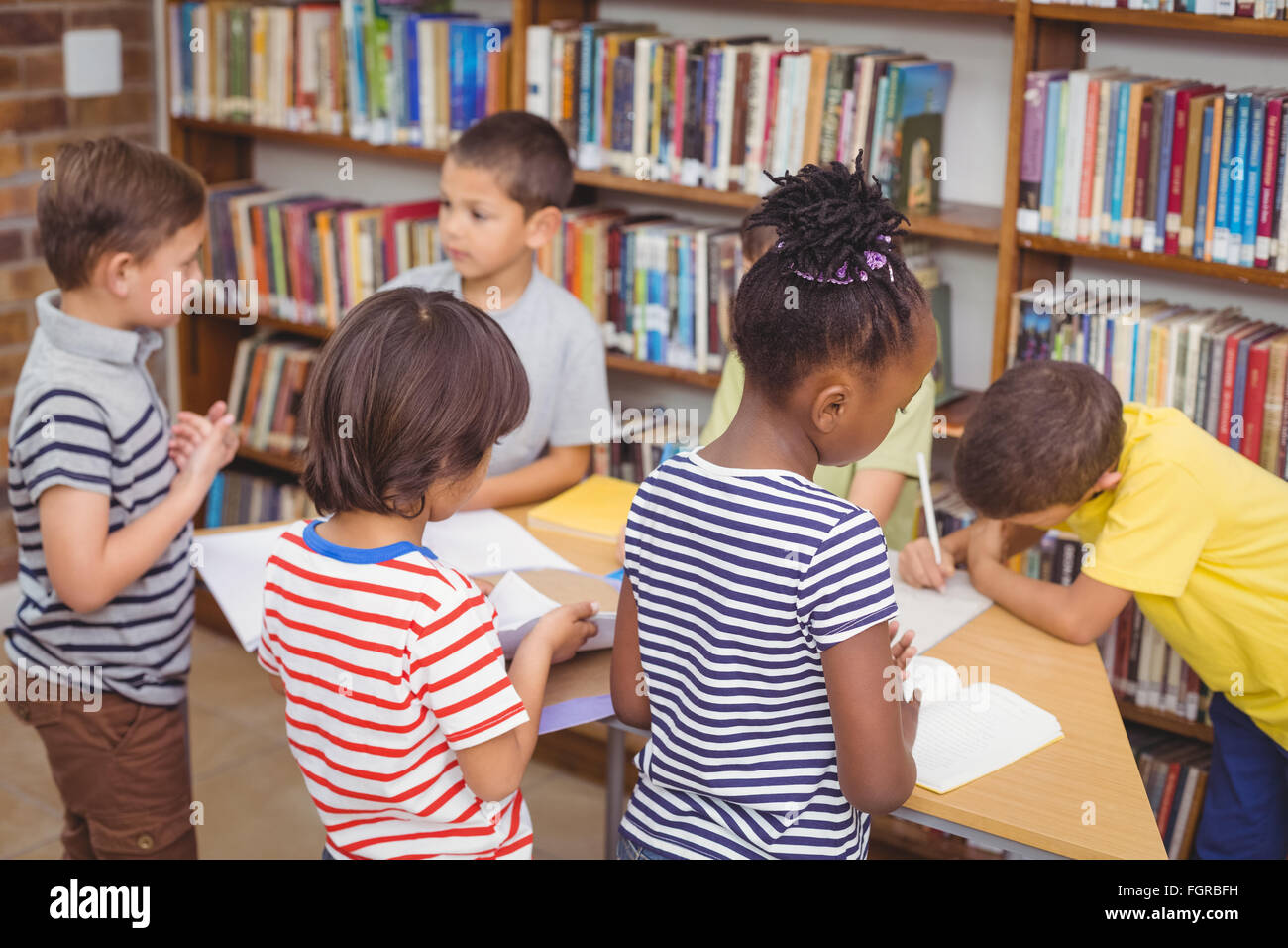 Pupils working together at desk in library Stock Photo - Alamy