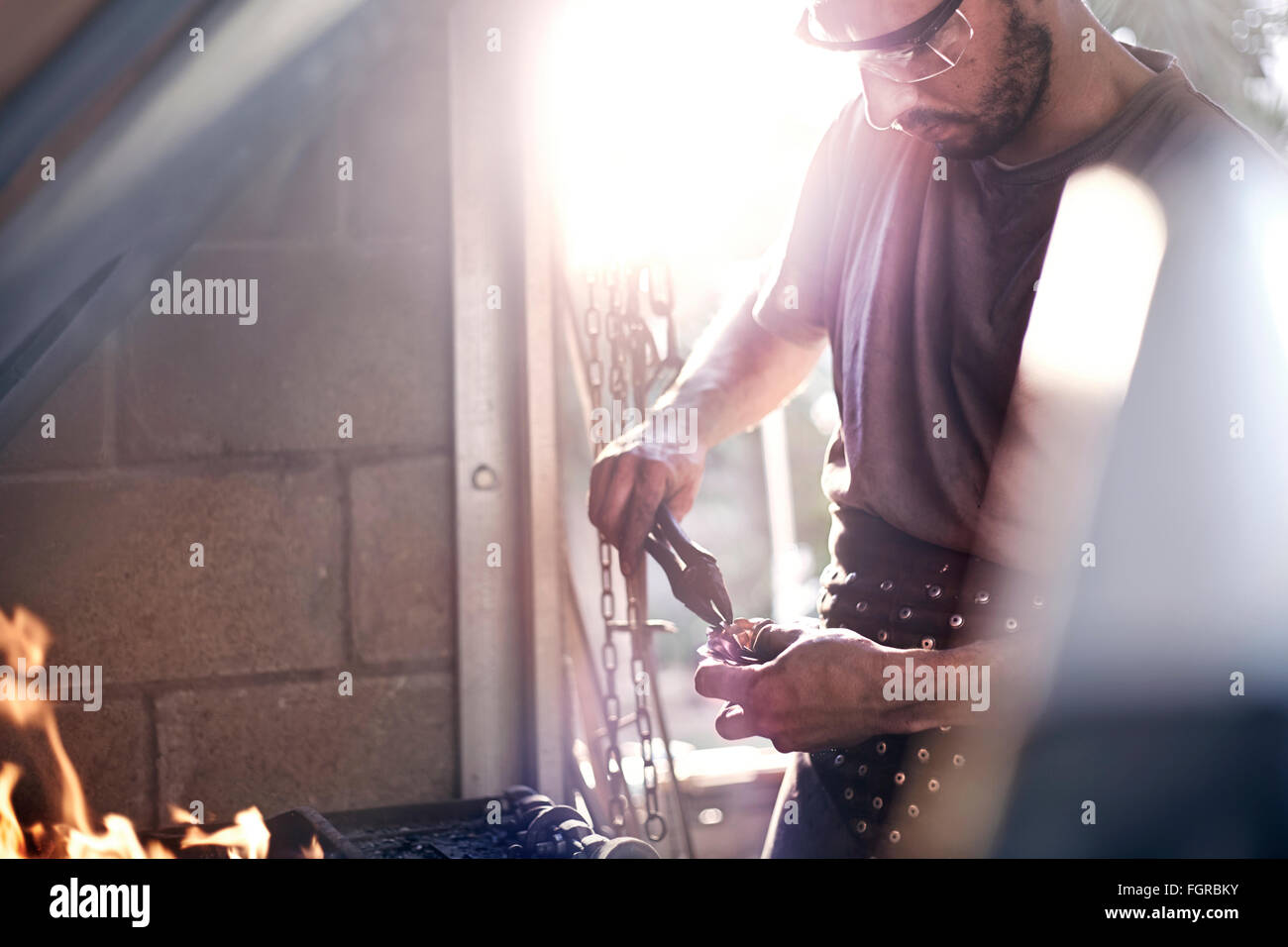 Blacksmith using pliers at fire in forge Stock Photo - Alamy