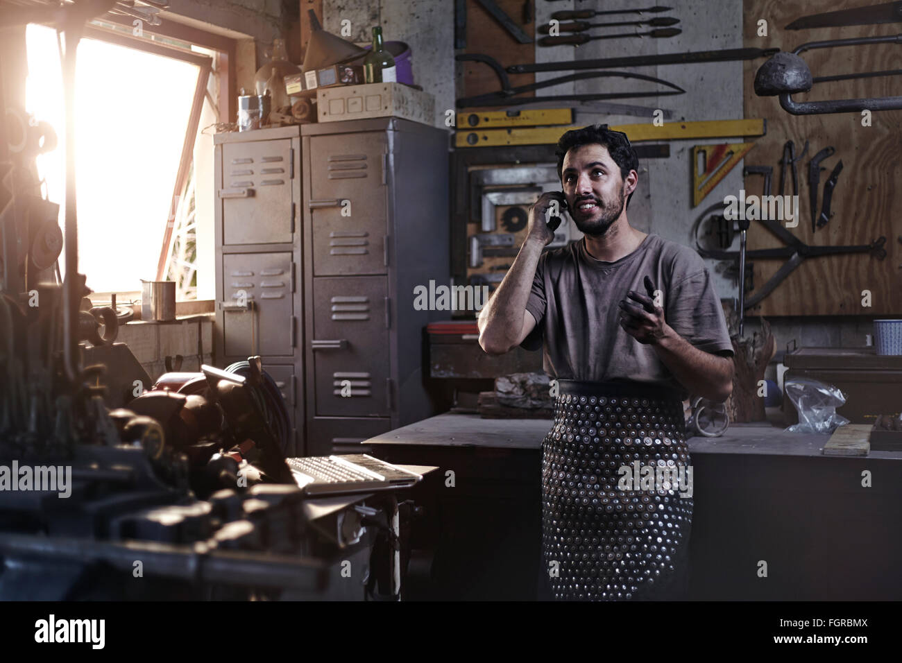 Blacksmith talking on cell phone in forge Stock Photo - Alamy