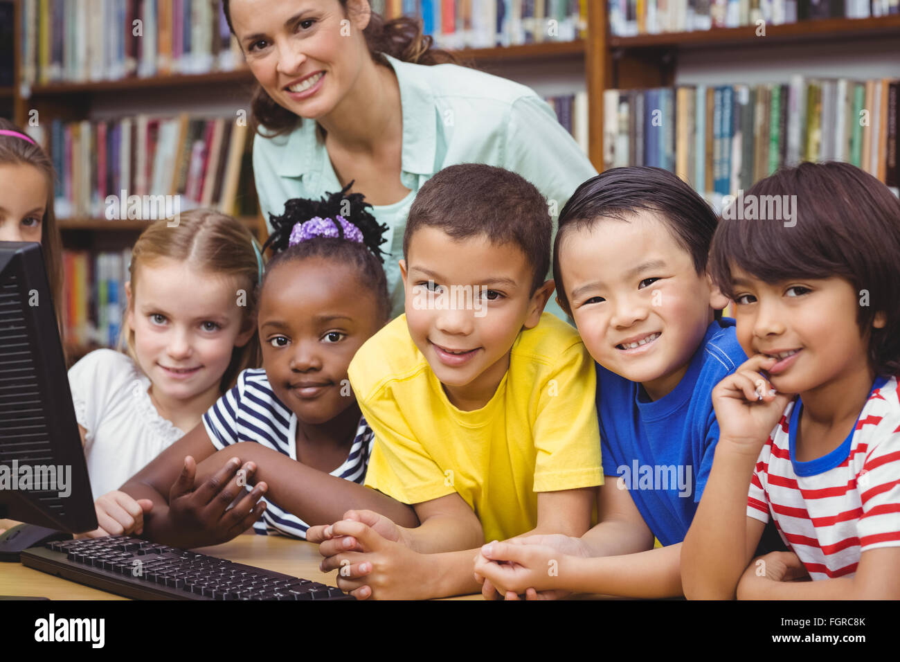 Pupils and teacher in the library using computer Stock Photo - Alamy