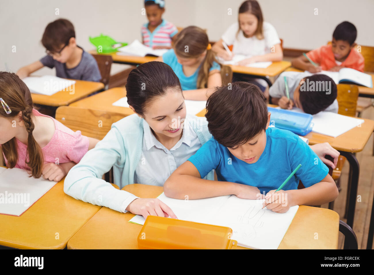 Teacher helping a little boy during class Stock Photo - Alamy