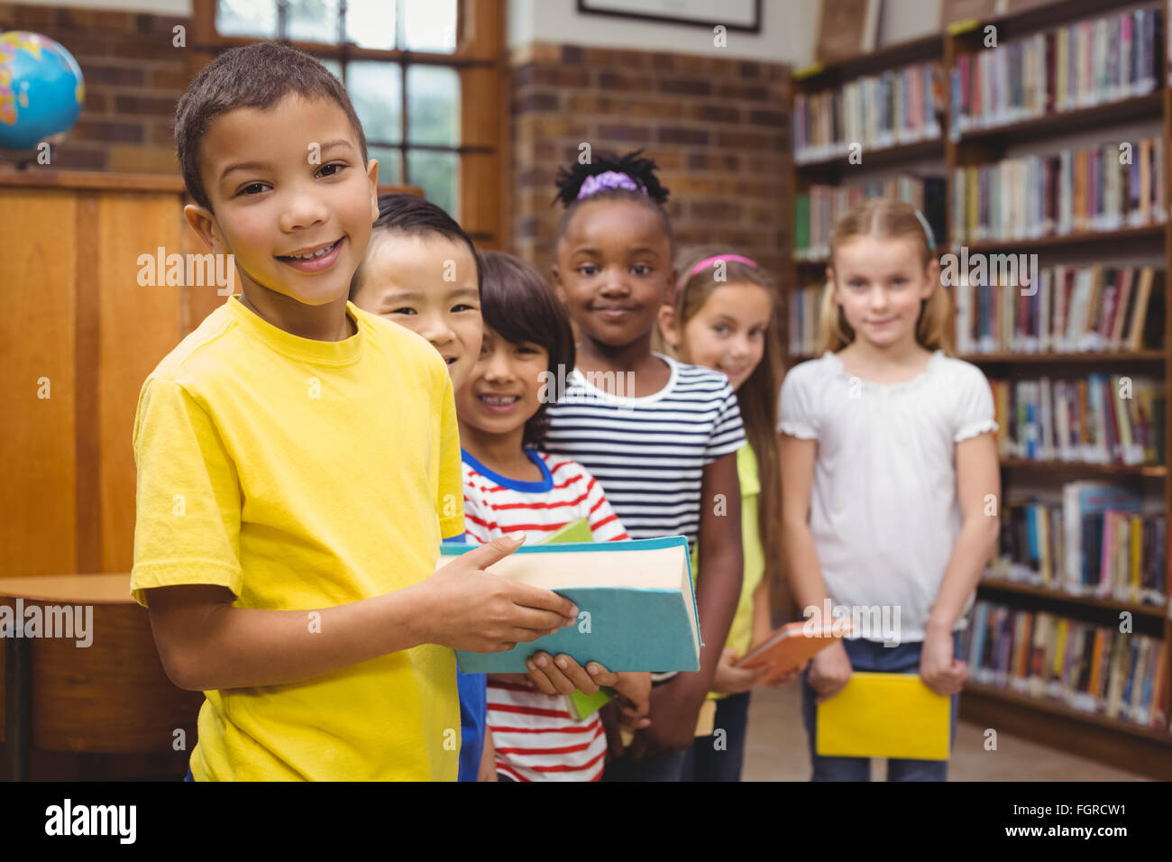 Pupils holding books from shelf in library Stock Photo - Alamy