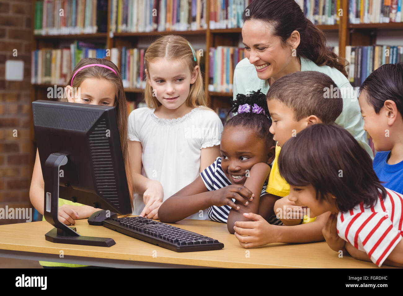 Pupils and teacher in the library using computer Stock Photo - Alamy