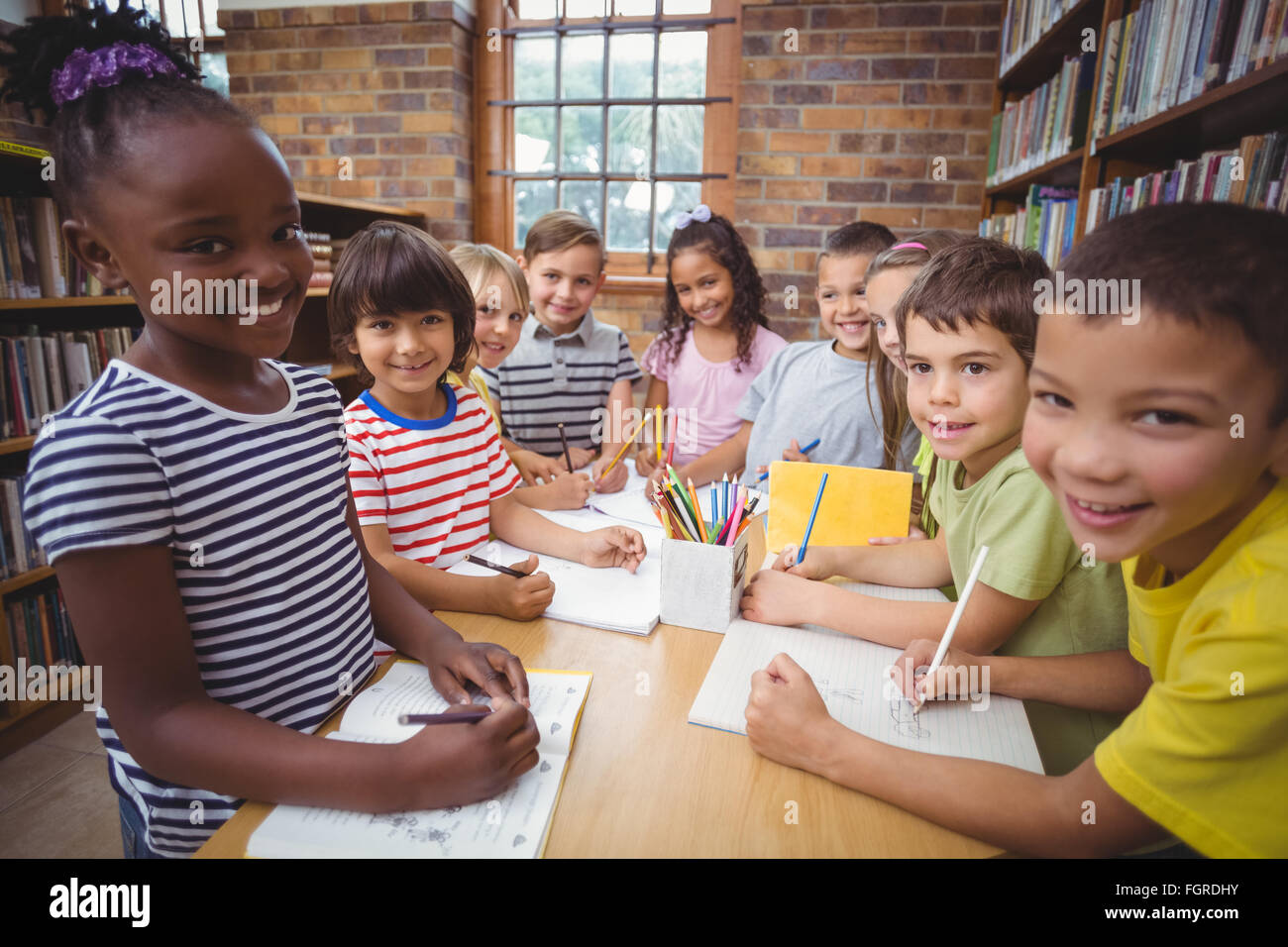 Pupils working together at desk in library Stock Photo - Alamy