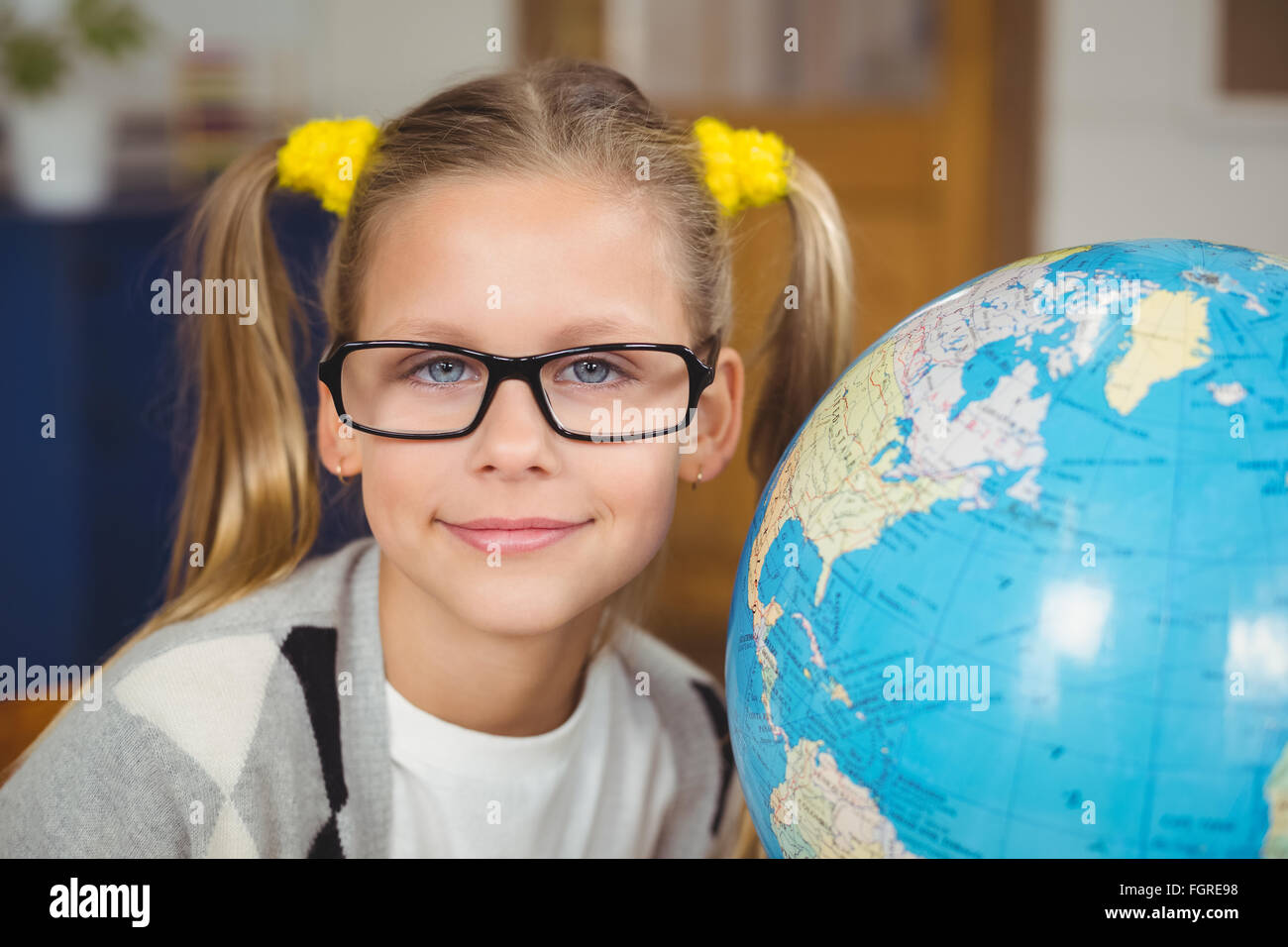 Cute pupil smiling next to globe in a classroom Stock Photo - Alamy