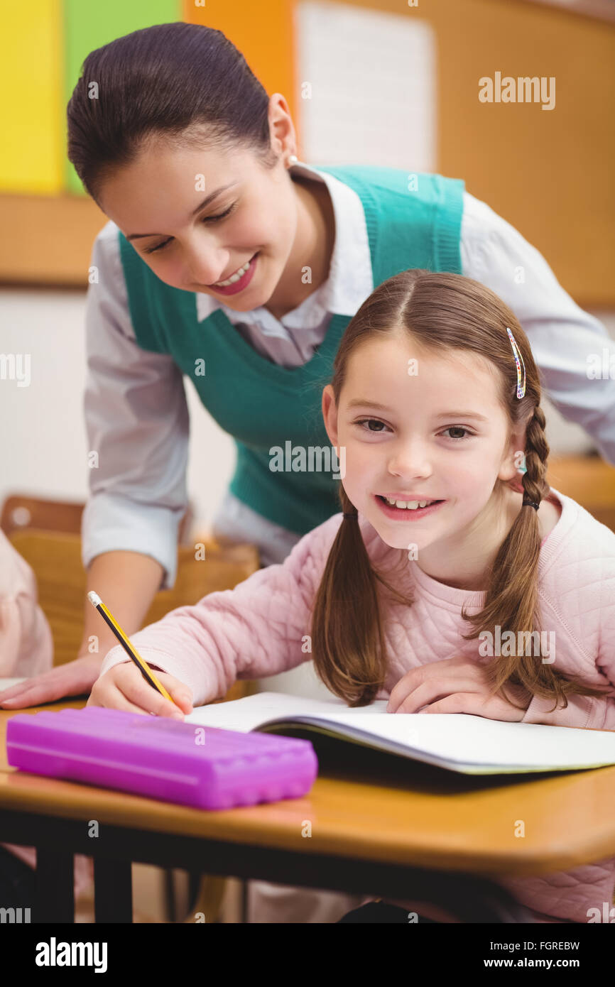 Teacher helping a little girl during class Stock Photo - Alamy