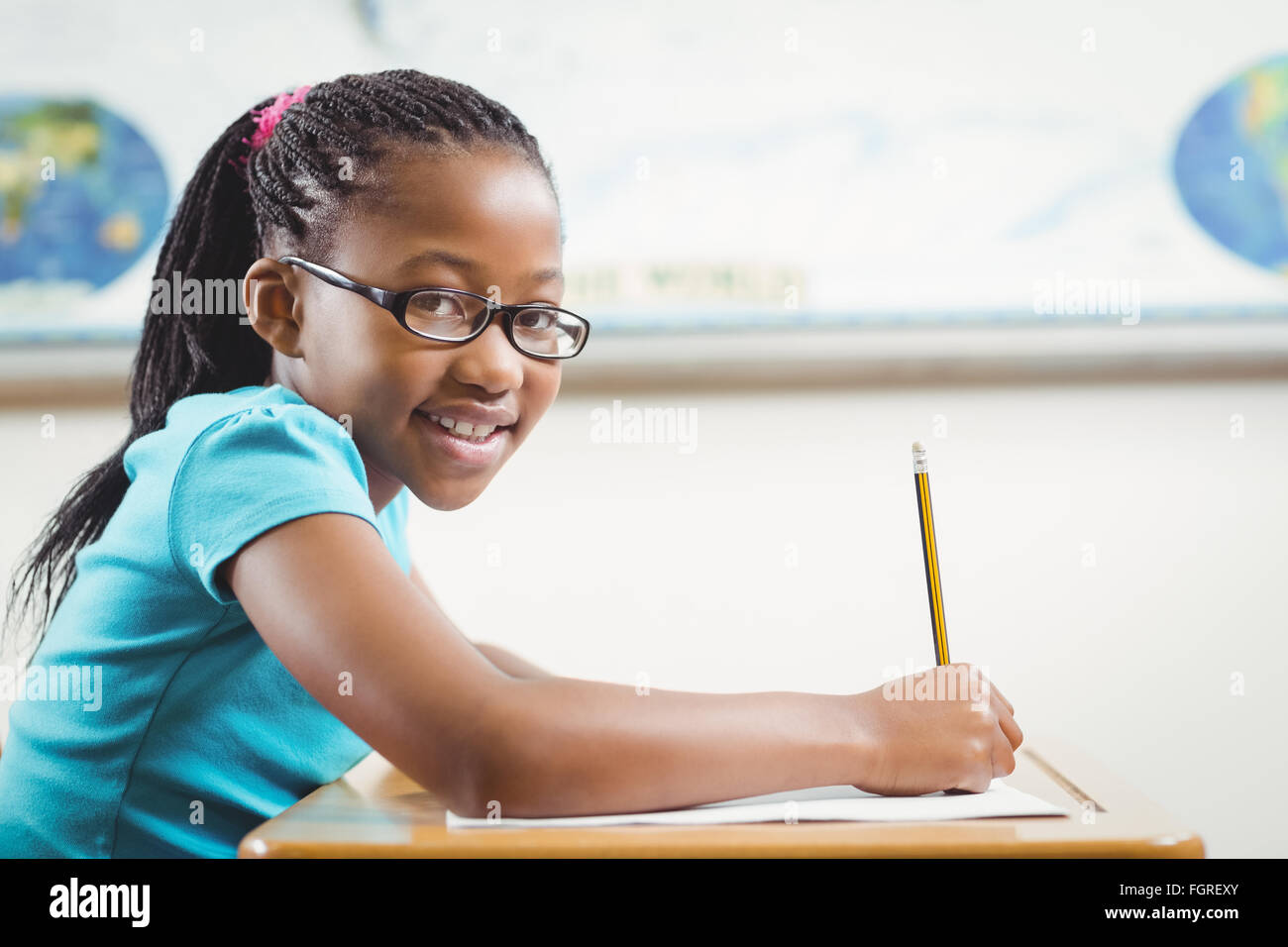 Smiling pupil working at her desk in a classroom Stock Photo - Alamy