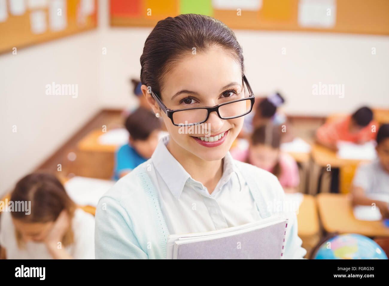 Teacher smiling at camera in classroom Stock Photo - Alamy