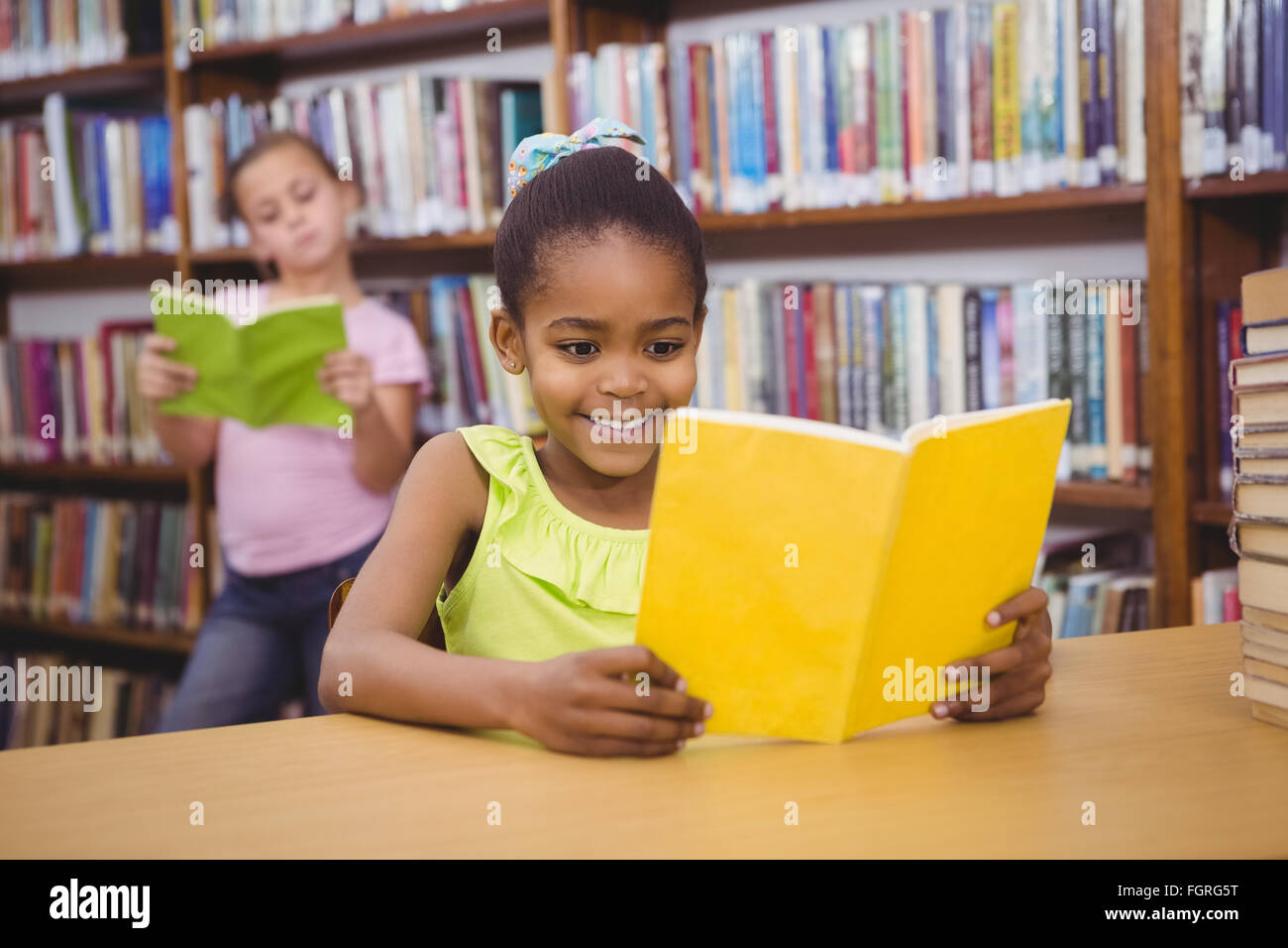 Happy pupil reading a library book Stock Photo - Alamy