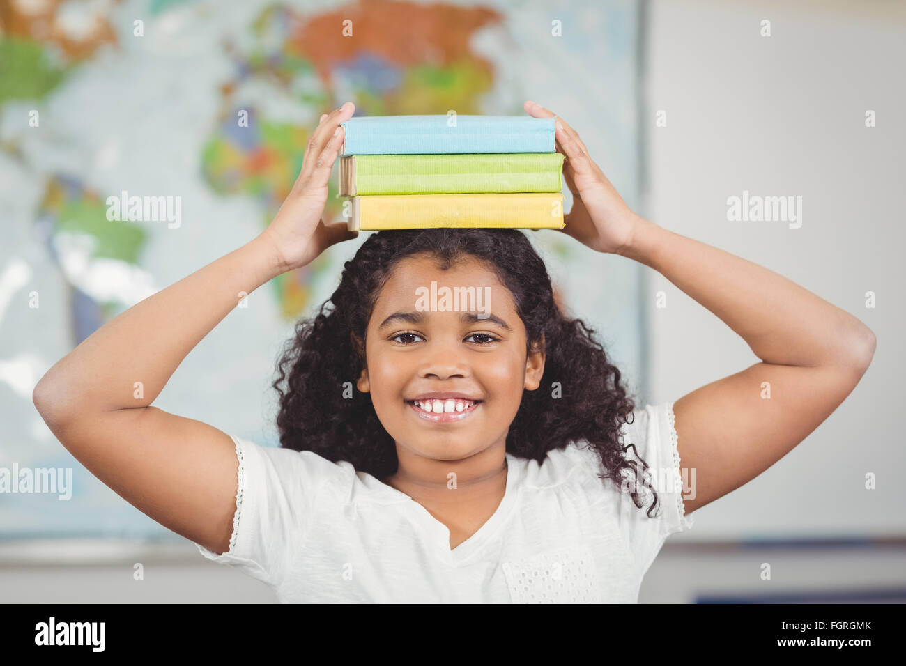 Smiling pupil balancing books on head in a classroom Stock Photo - Alamy