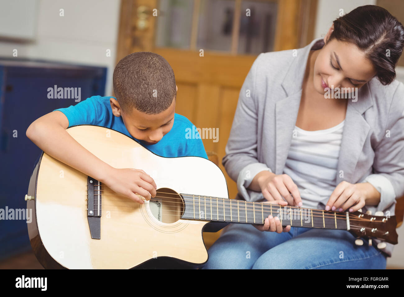 Pretty teacher giving guitar lessons to pupil Stock Photo - Alamy
