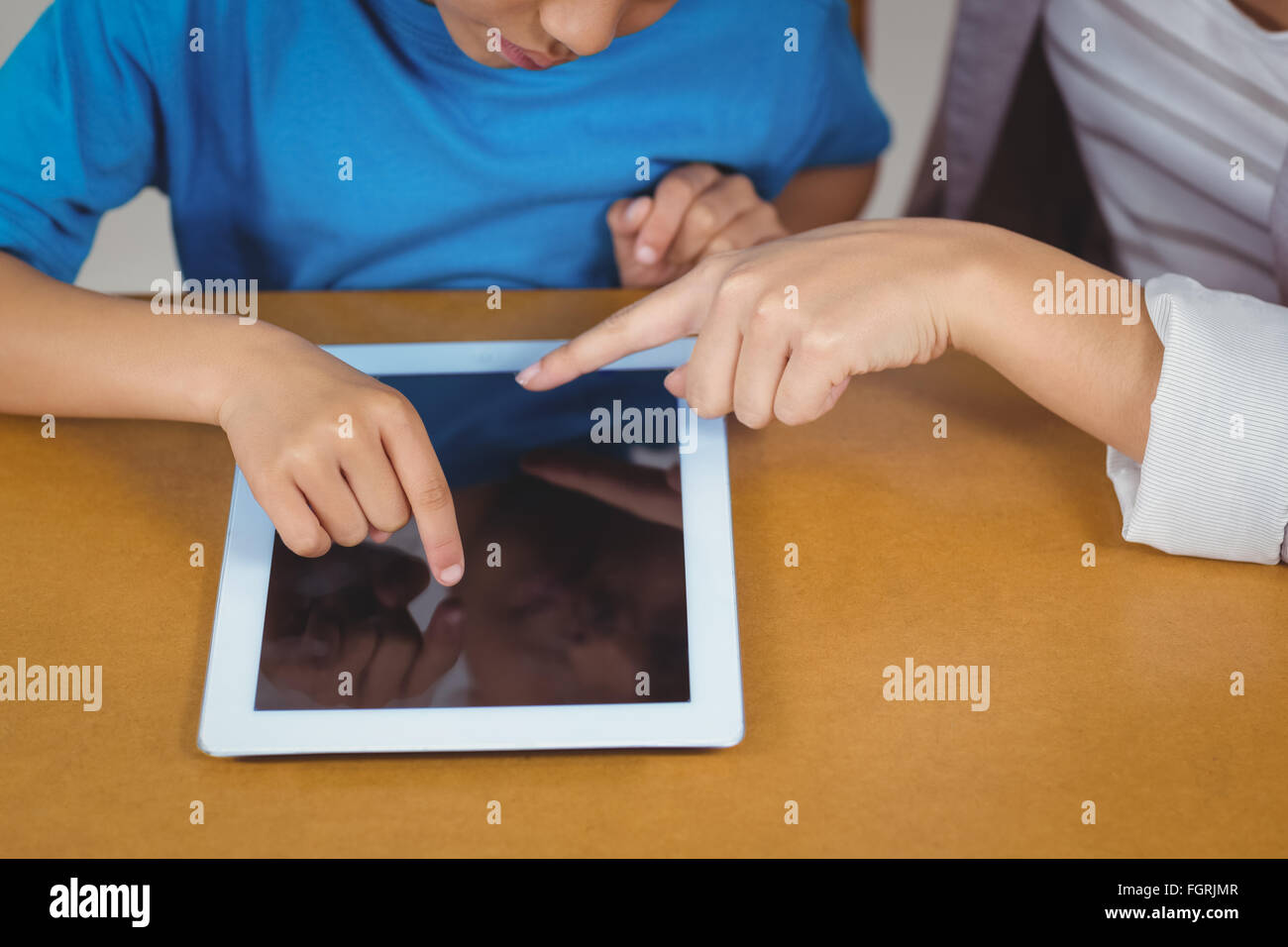Teacher and pupil using tablet at his desk Stock Photo - Alamy