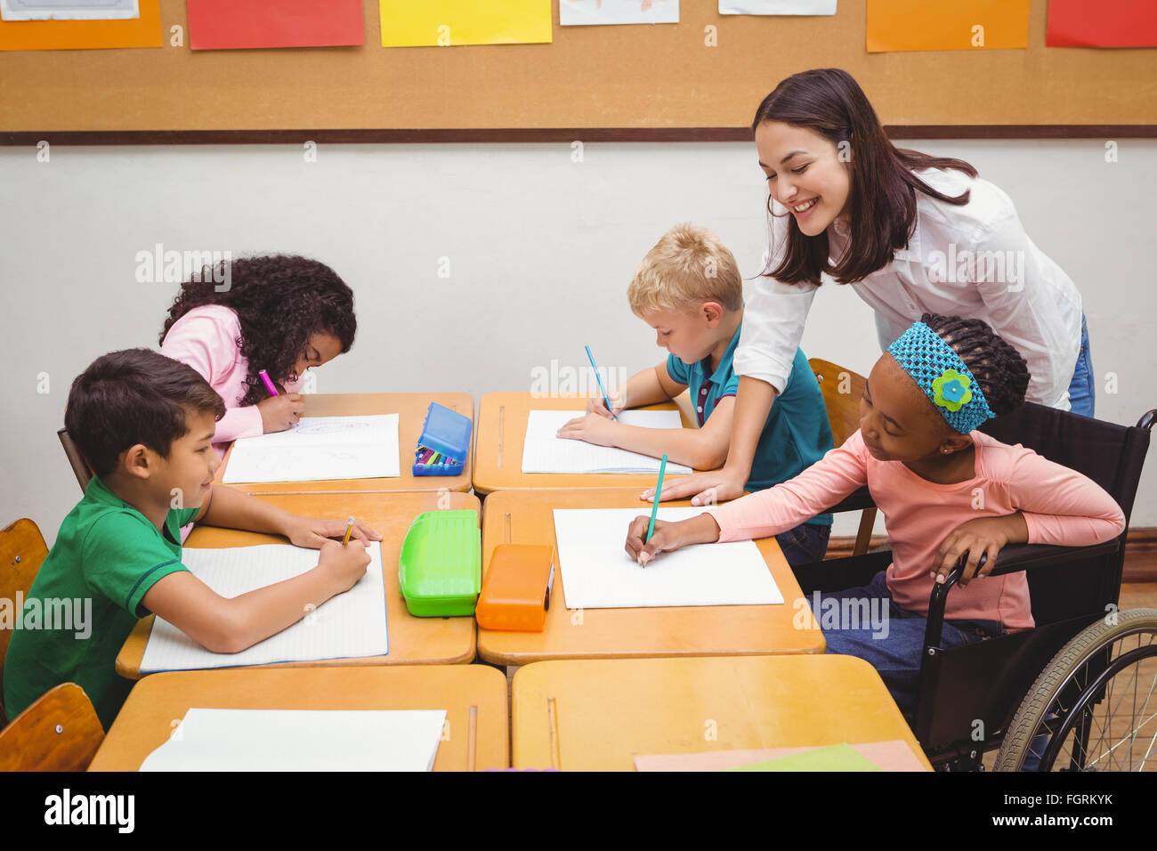 Happy teacher helping her students Stock Photo - Alamy