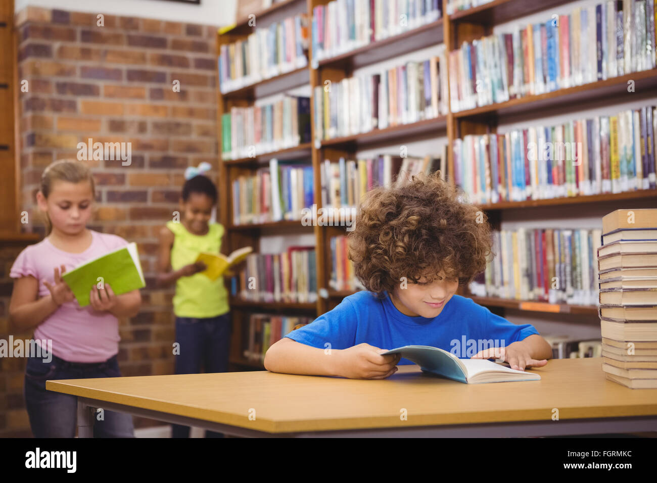 Happy pupil reading a library book Stock Photo - Alamy