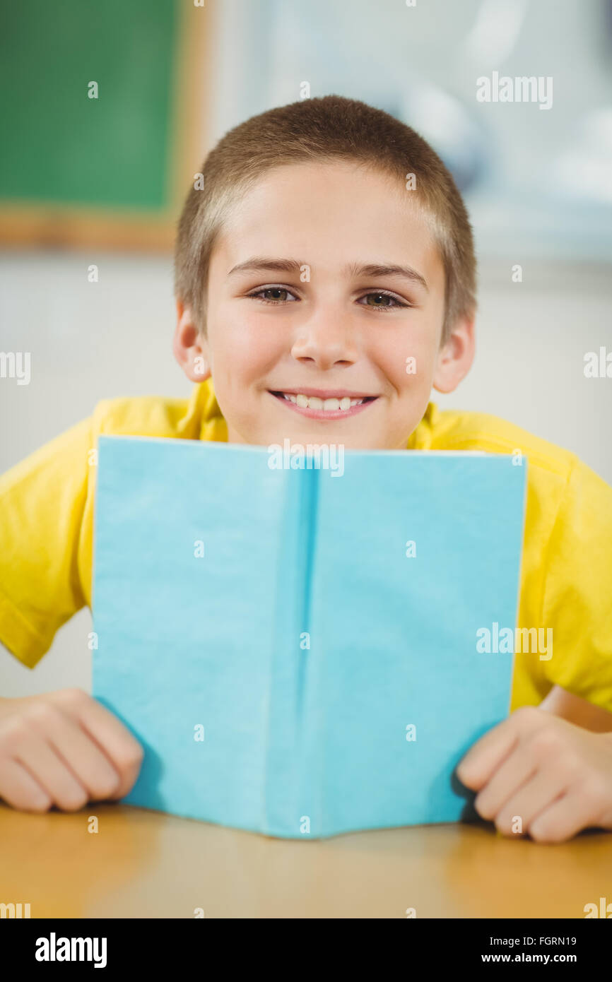 Smiling pupil reading book in a classroom Stock Photo - Alamy