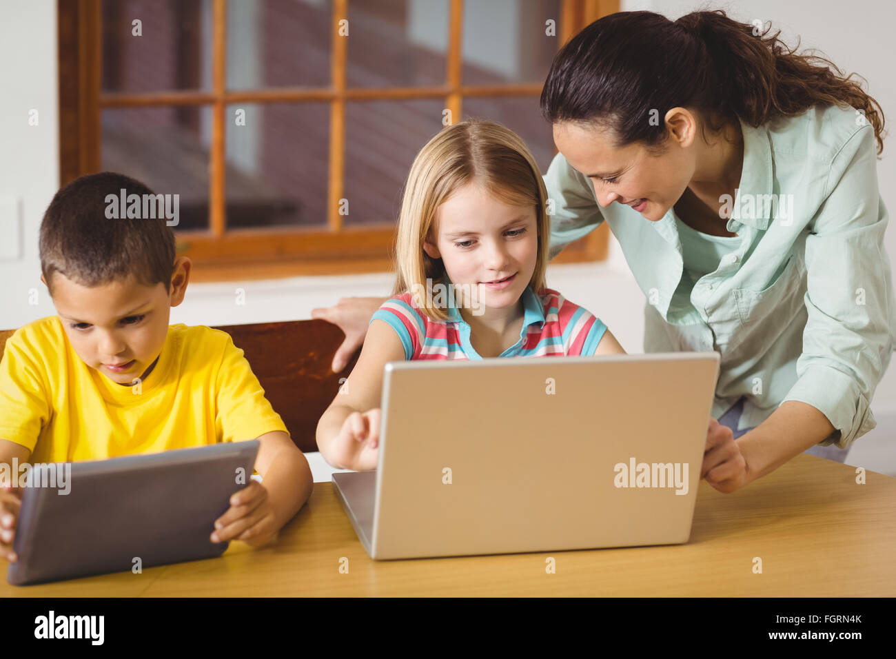 Cute pupils in class using laptop and tablet with teacher Stock Photo ...