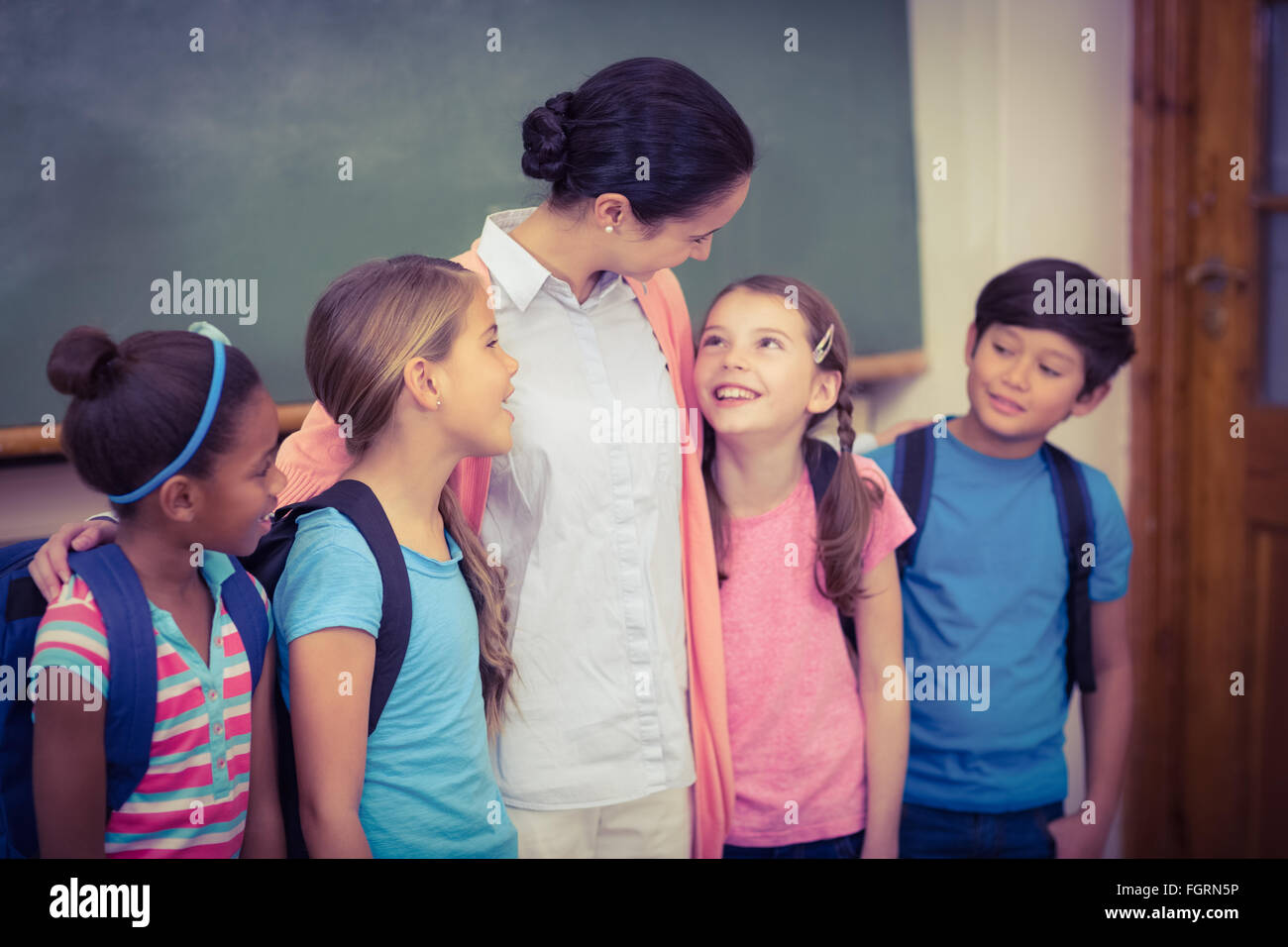 Teacher and pupils smiling in classroom Stock Photo - Alamy