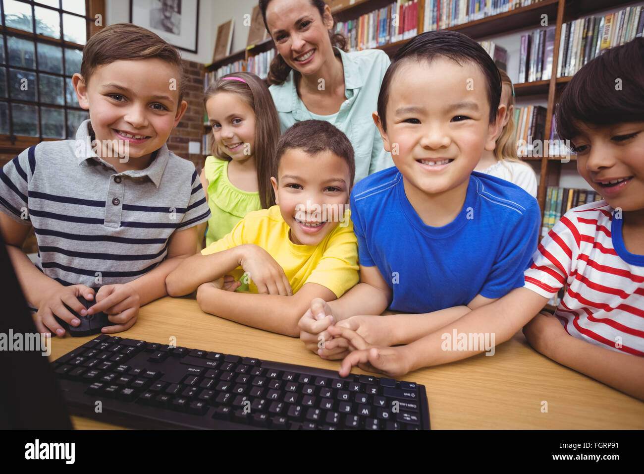 Pupils and teacher in the library using computer Stock Photo - Alamy