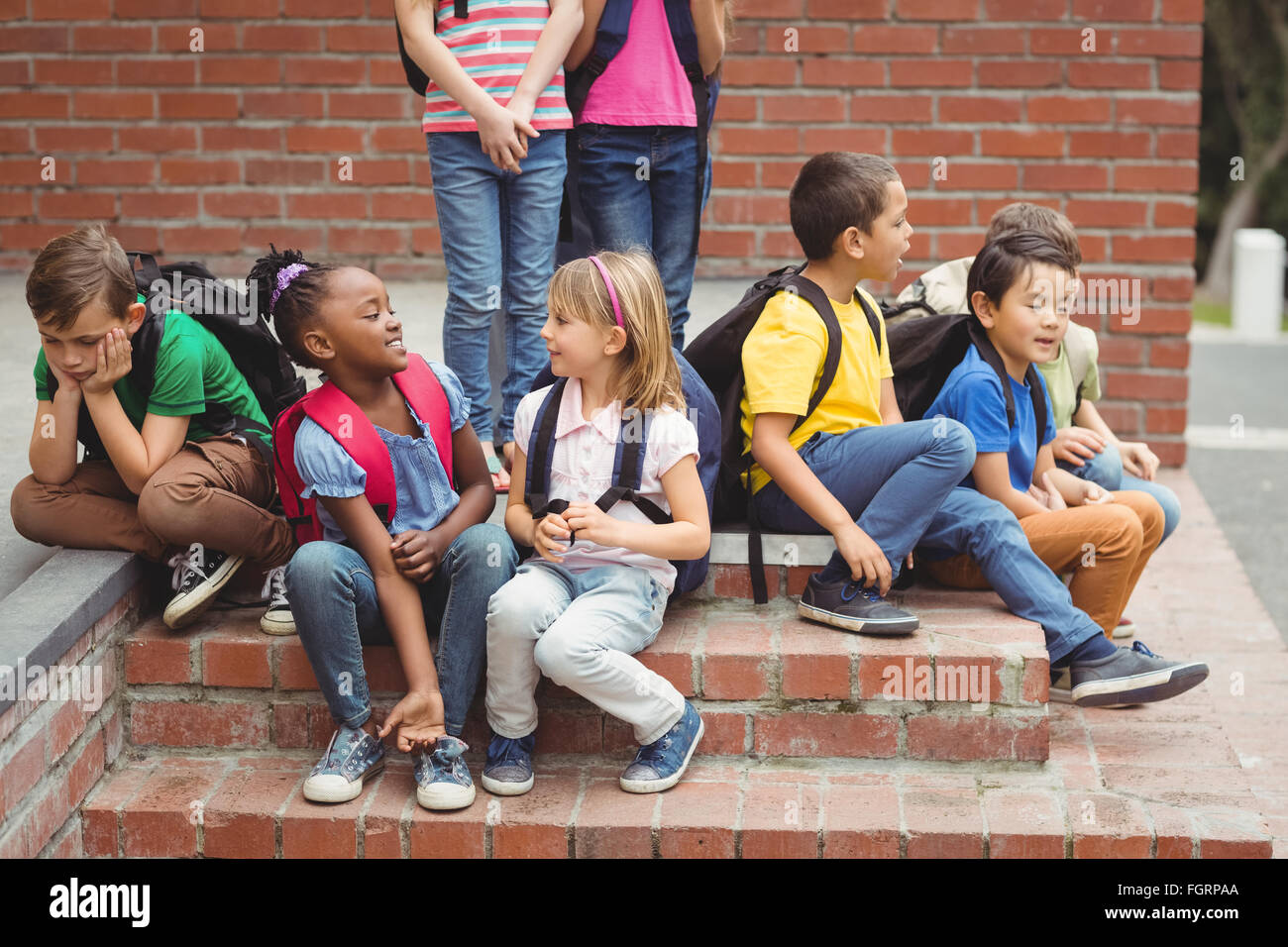 Cute pupils sitting on steps outside Stock Photo - Alamy