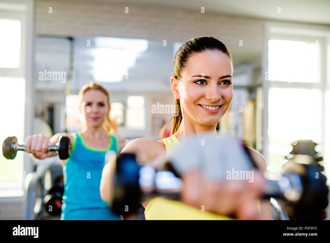 Two fit women in gym working out with weights Stock Photo - Alamy