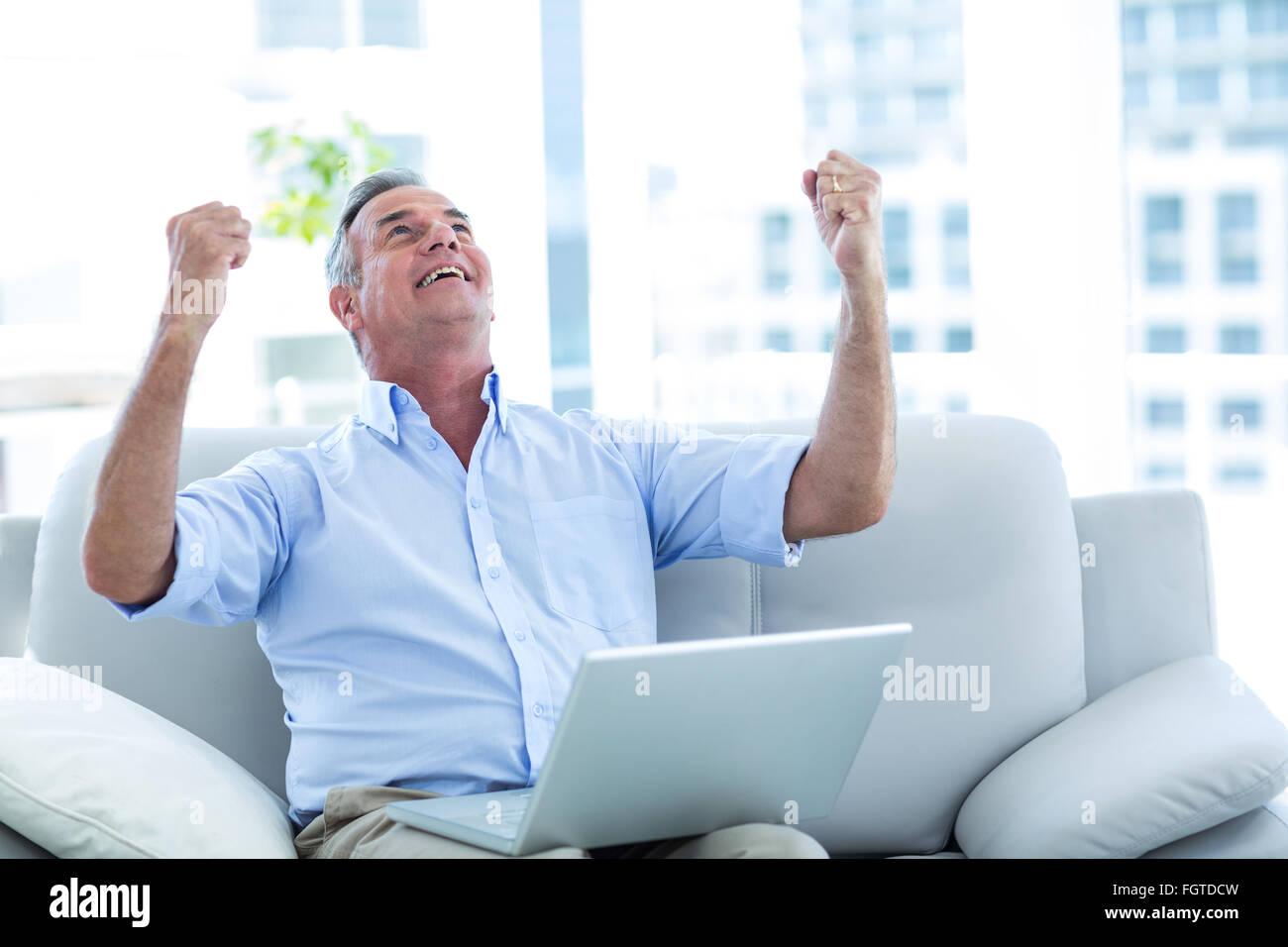 Happy man looking up while working on laptop Stock Photo - Alamy