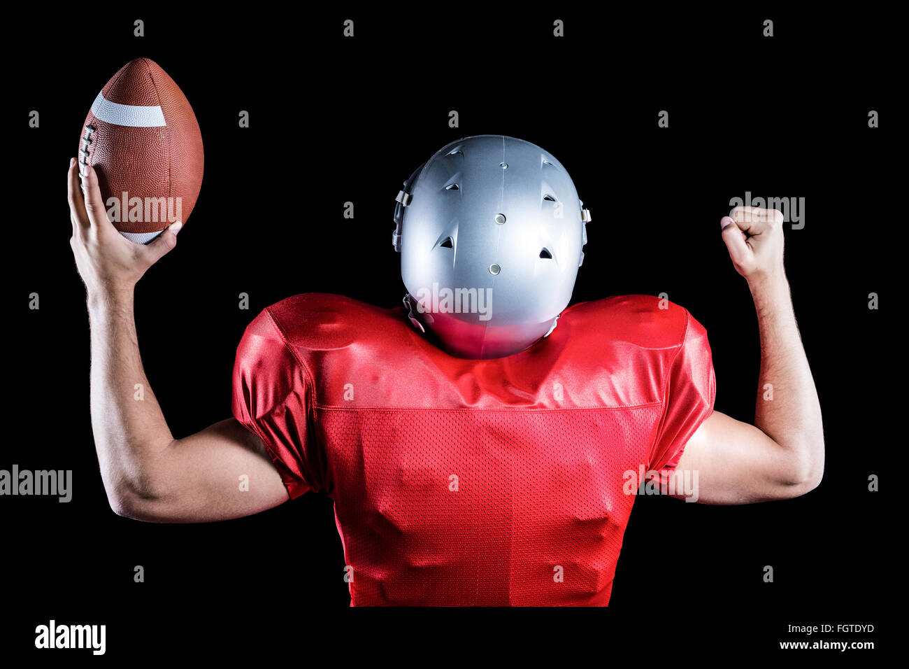 Rear view of American football player cheering while holding ball Stock ...