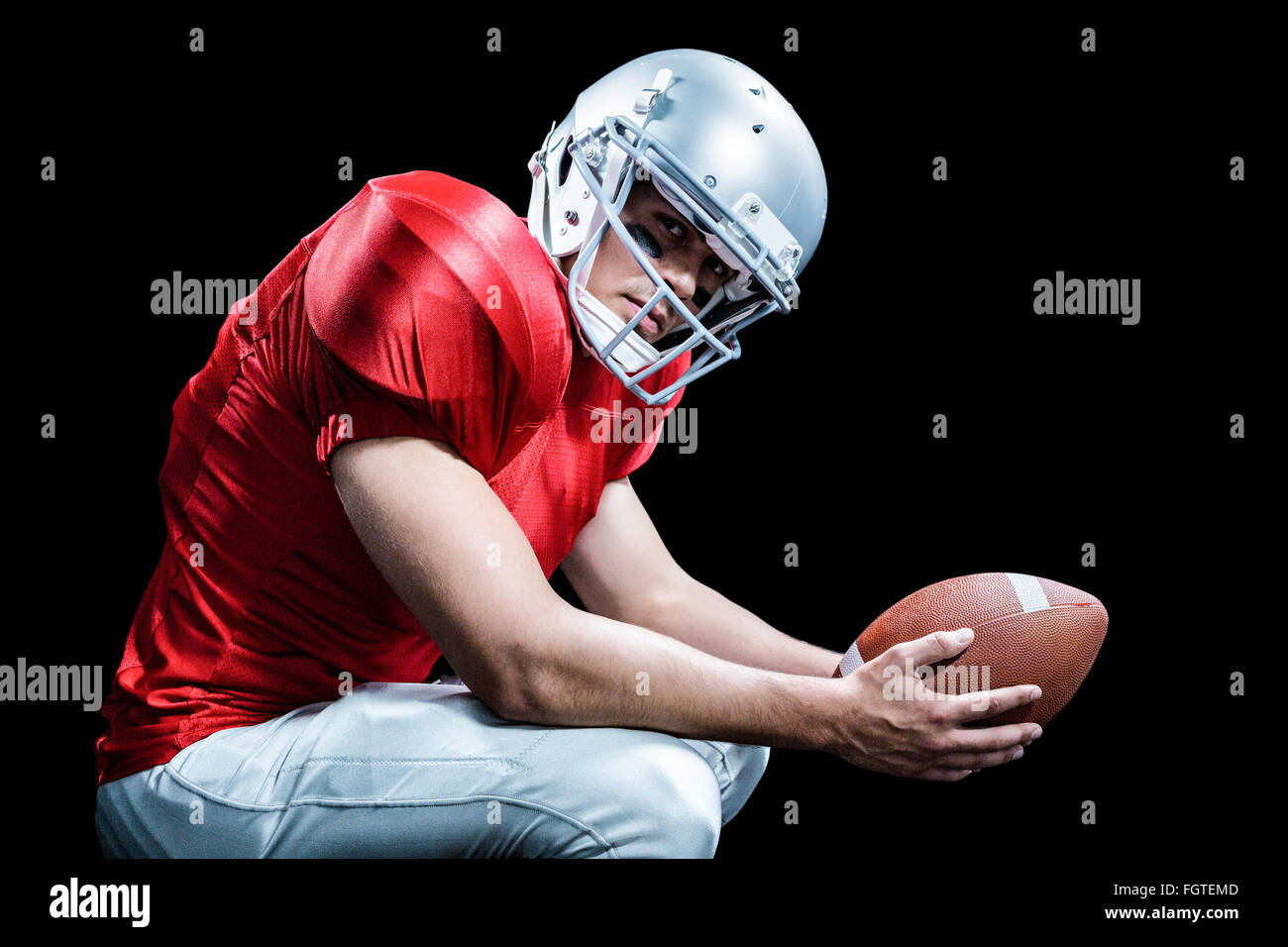 Portrait of American football player crouching while holding ball Stock ...