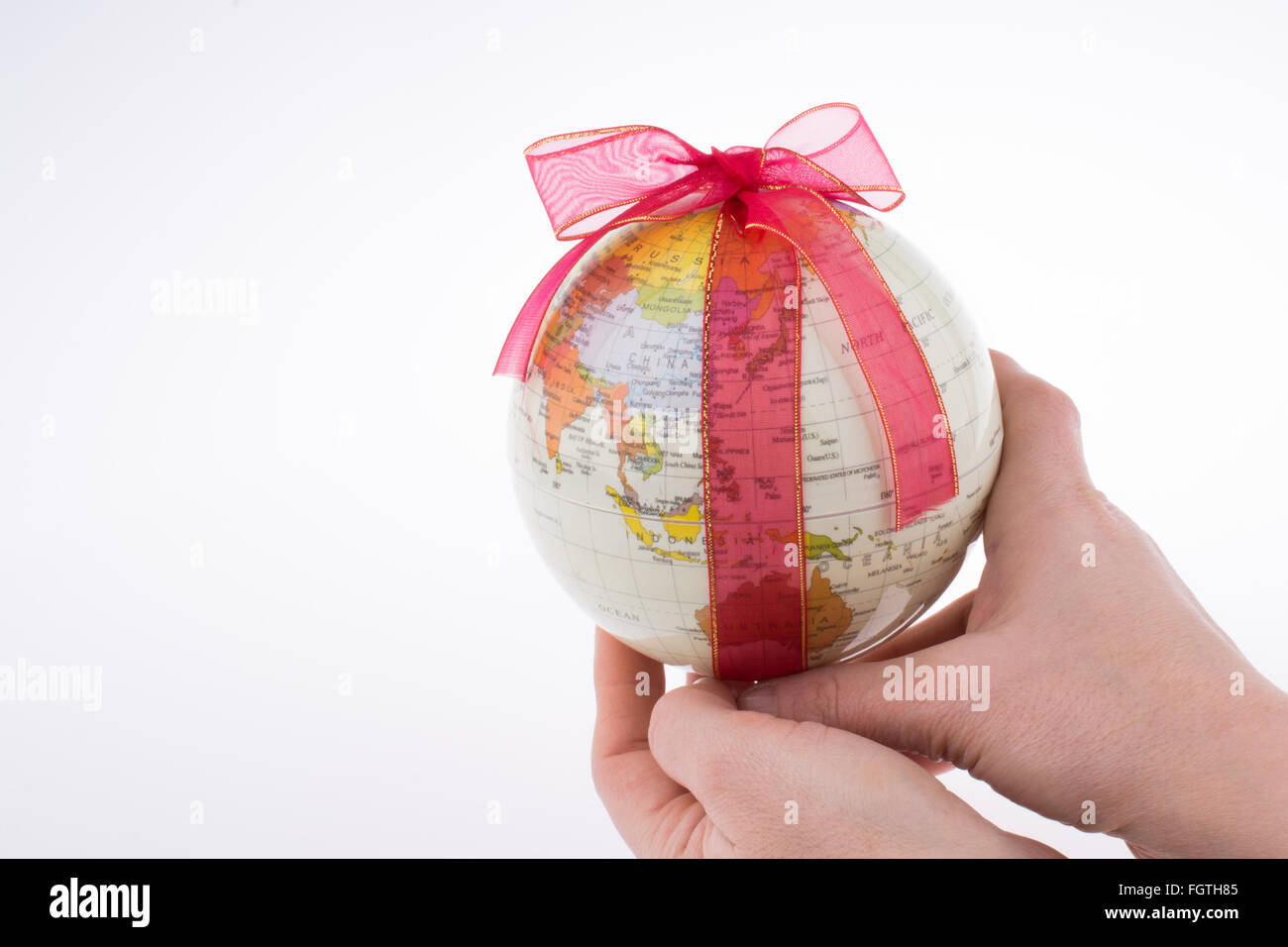 Globe tied with red ribbon on a white background Stock Photo - Alamy