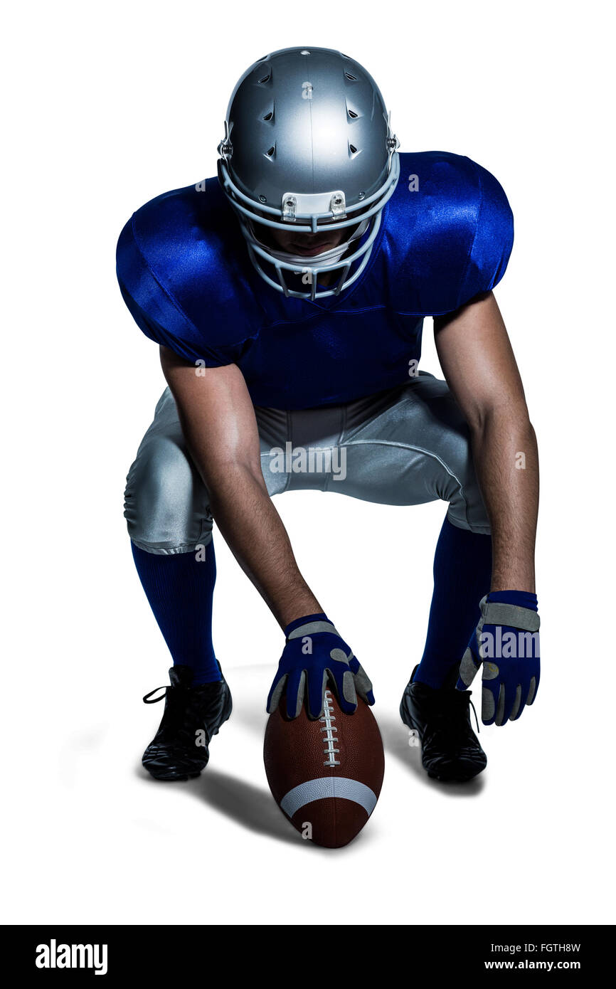 American football player holding ball while crouching Stock Photo - Alamy