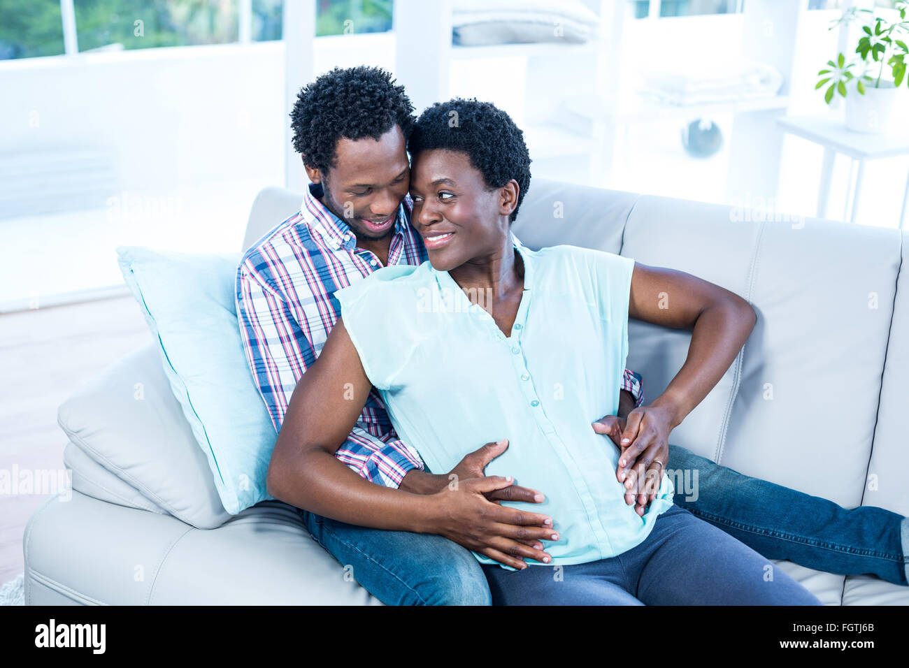 Couple embracing while sitting on couch Stock Photo - Alamy