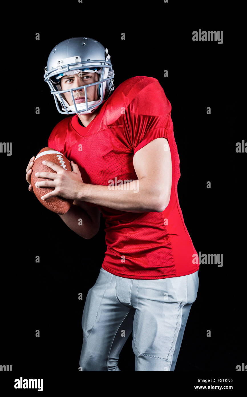 Determined American football player holding ball Stock Photo - Alamy