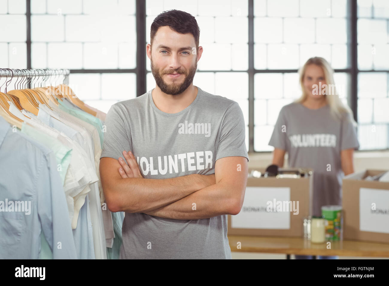 Portrait of happy man with arms crossed standing by clothes rack Stock ...