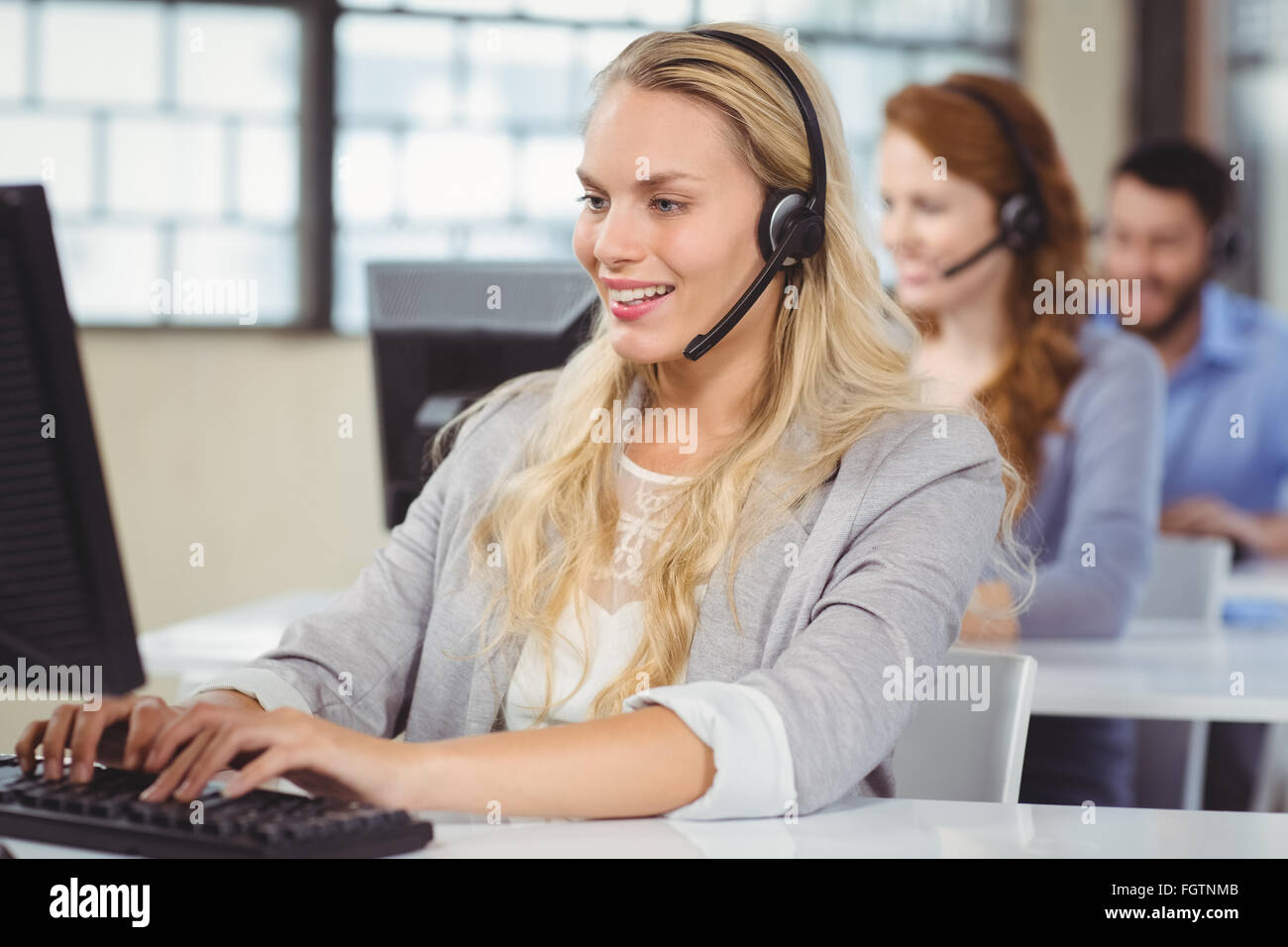Woman speaking over headset while working Stock Photo - Alamy