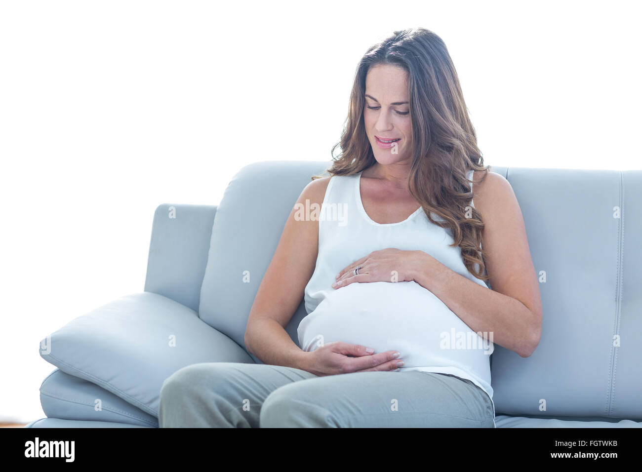 Pregnant woman sitting on sofa Stock Photo - Alamy