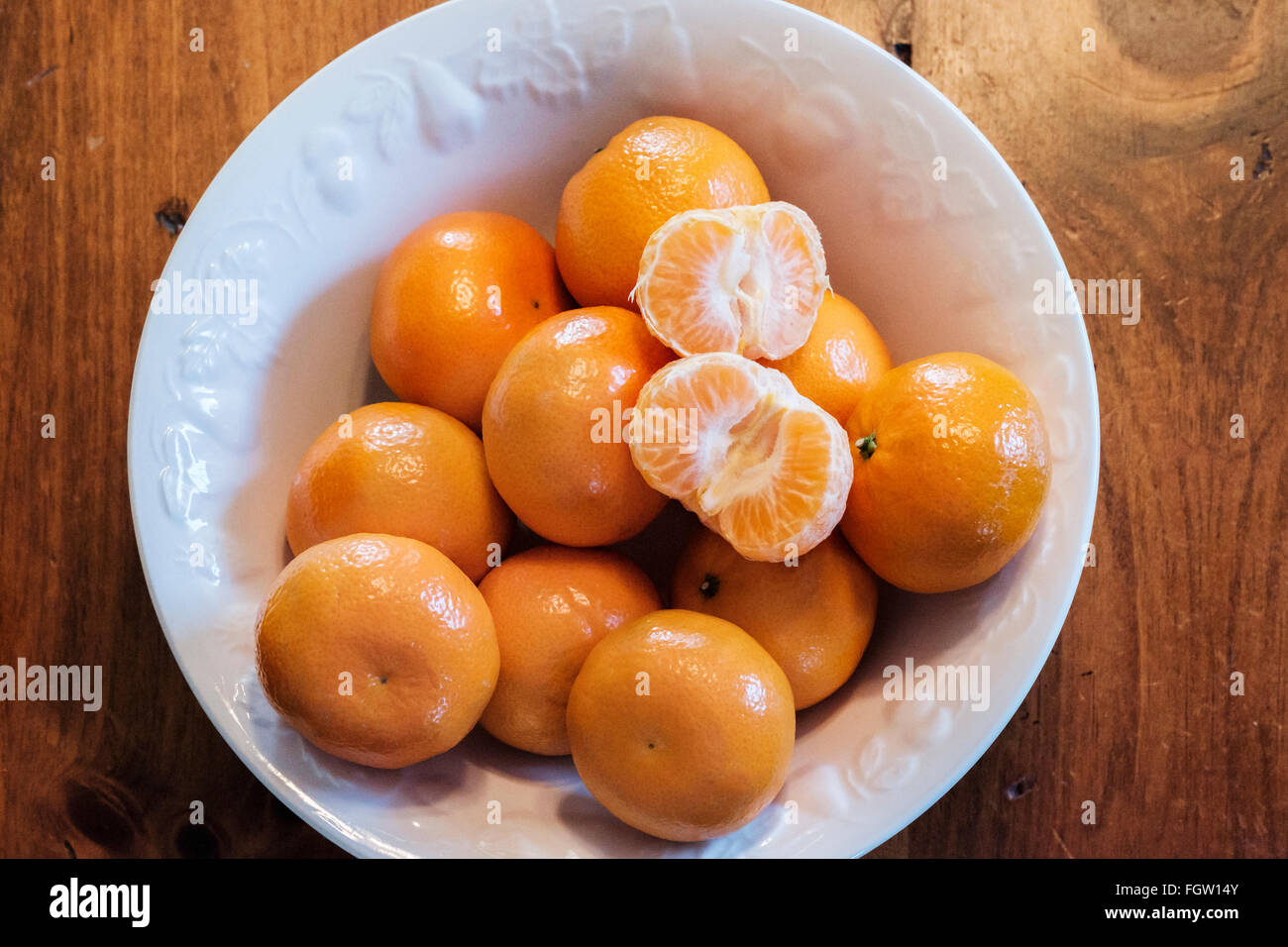 Mandarin oranges, Citrus reticulata, with one peeled, in a white bowl ...